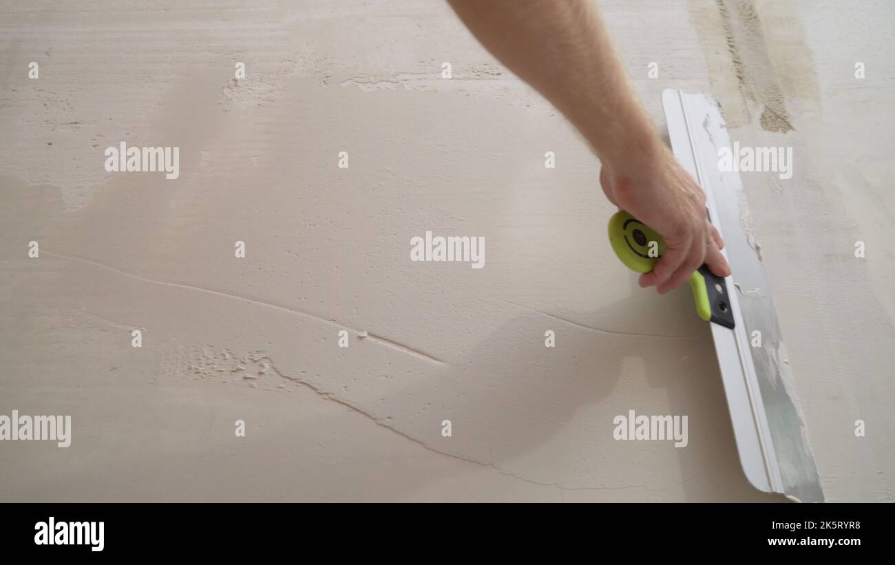 Builder smears a putty knife with a spatula. Worker puts mortar on a ...