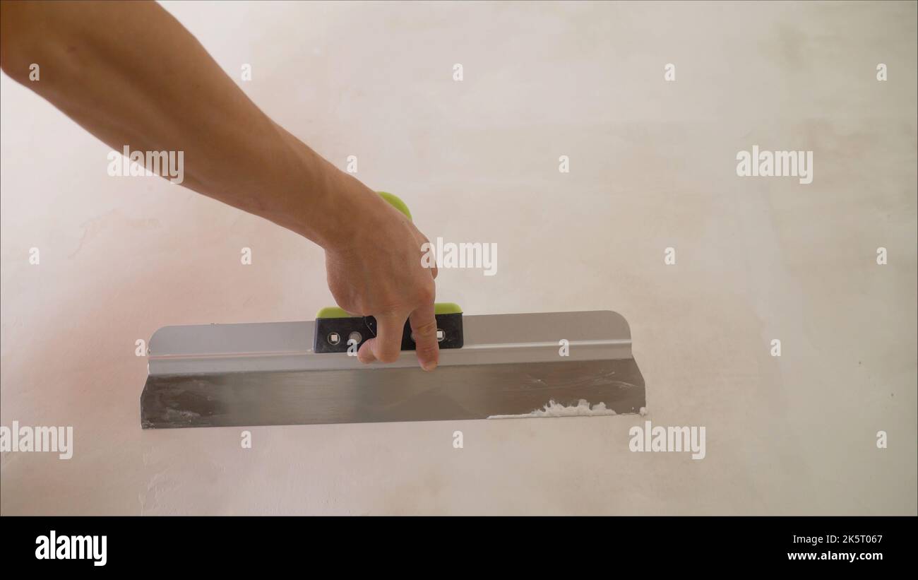 Worker spackles the walls with a spatula. Spatula with putty in hand ...