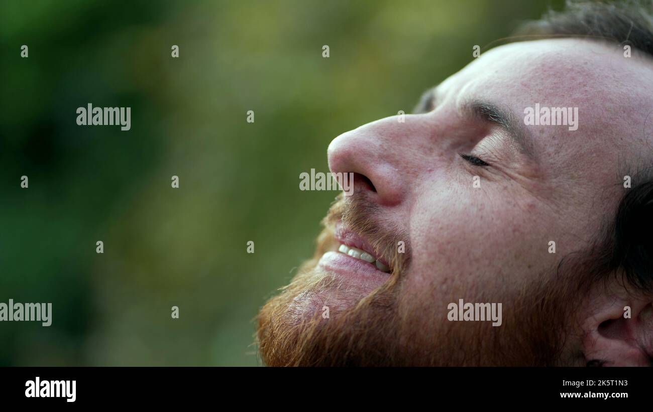 Grateful man closing eyes in meditation. Person opening eye to sky with ...