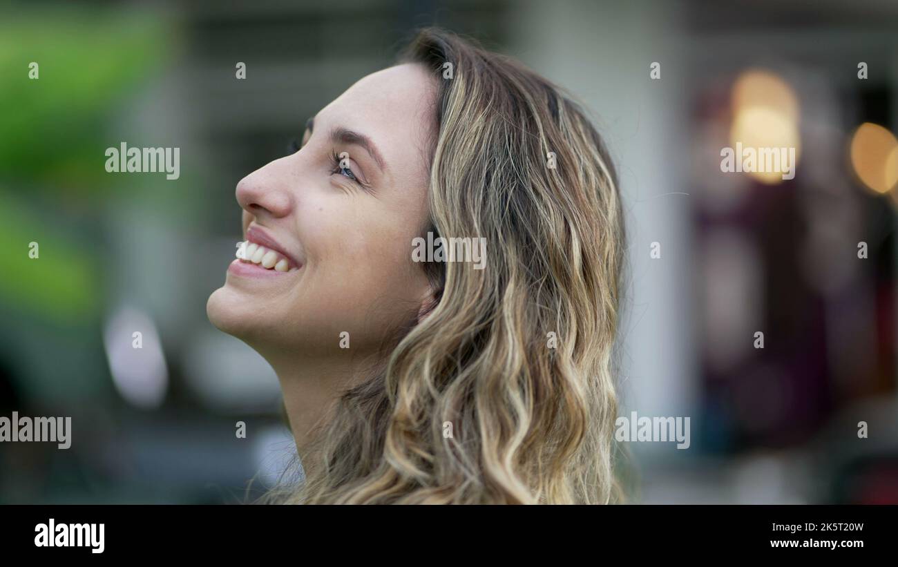 Happy young millennial woman staring at sky smiling in contemplation ...