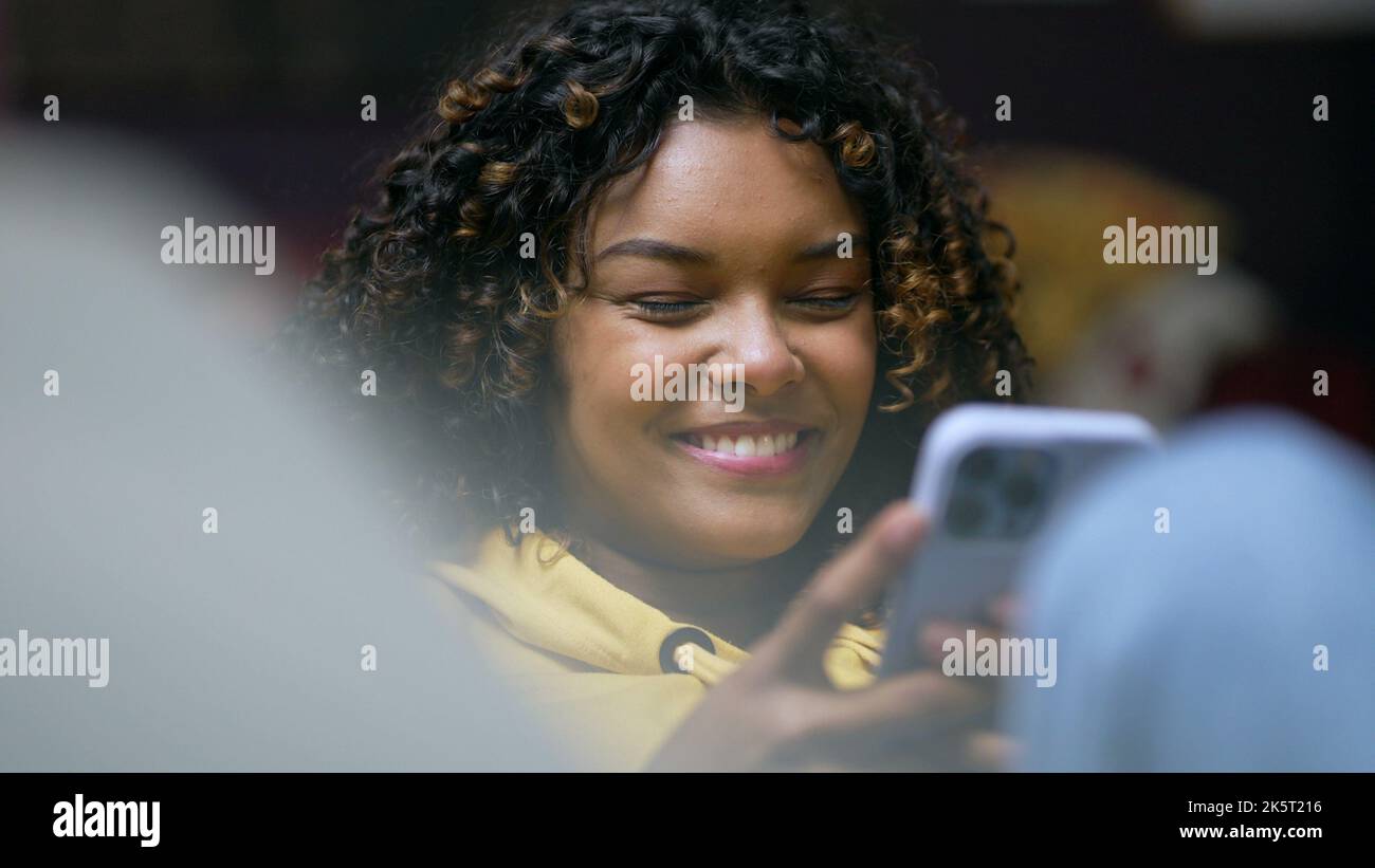 Happy young African American laughing and smiling while using phone at ...