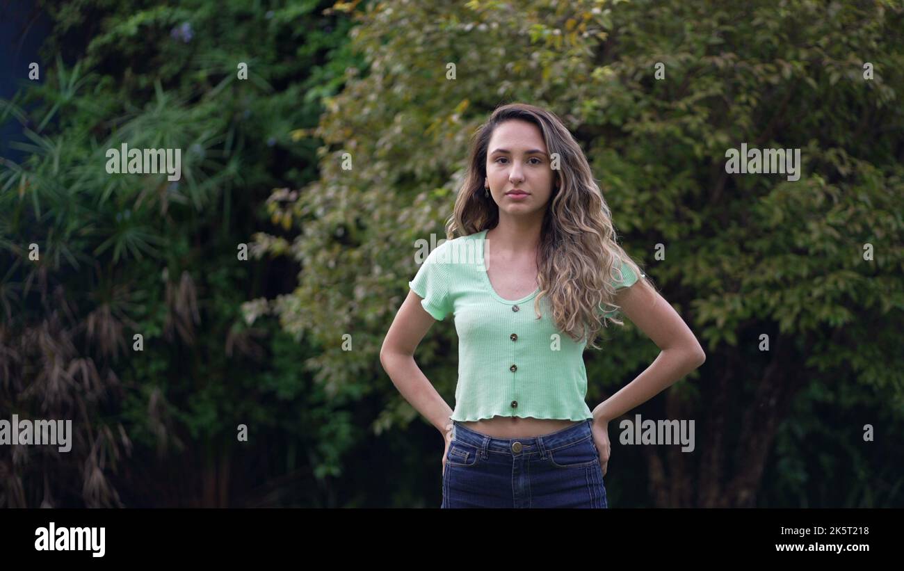 One happy young hispanic woman standing outdoors smiling at camera ...