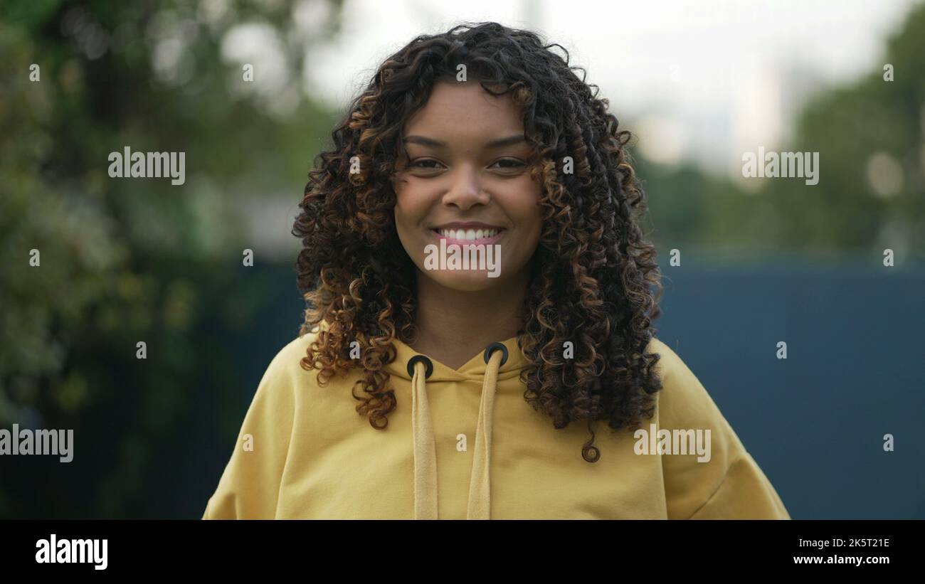 One joyful Brazilian black girl standing outdoors. 20s millennial ...
