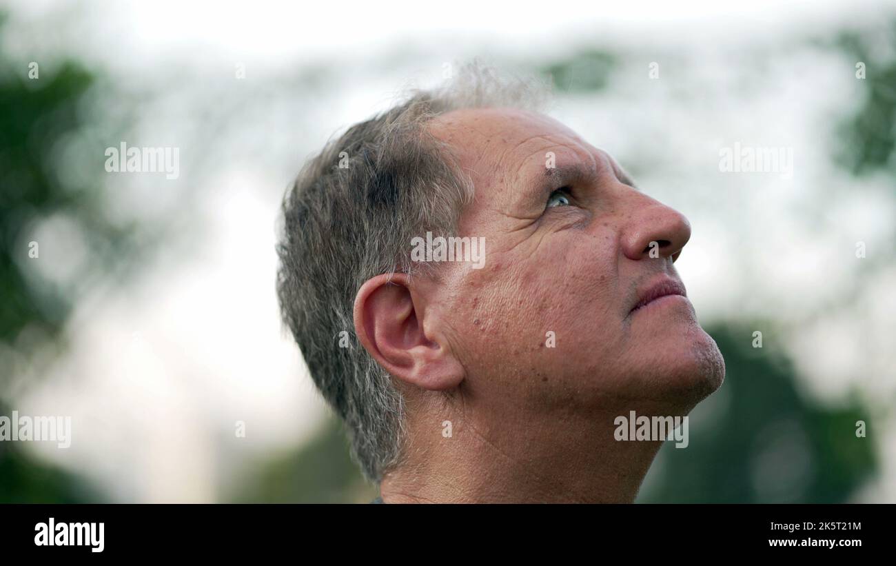Meditative One senior man looking up at sky with serious expression ...