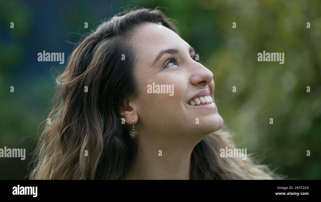 Happy young millennial woman staring at sky smiling in contemplation ...