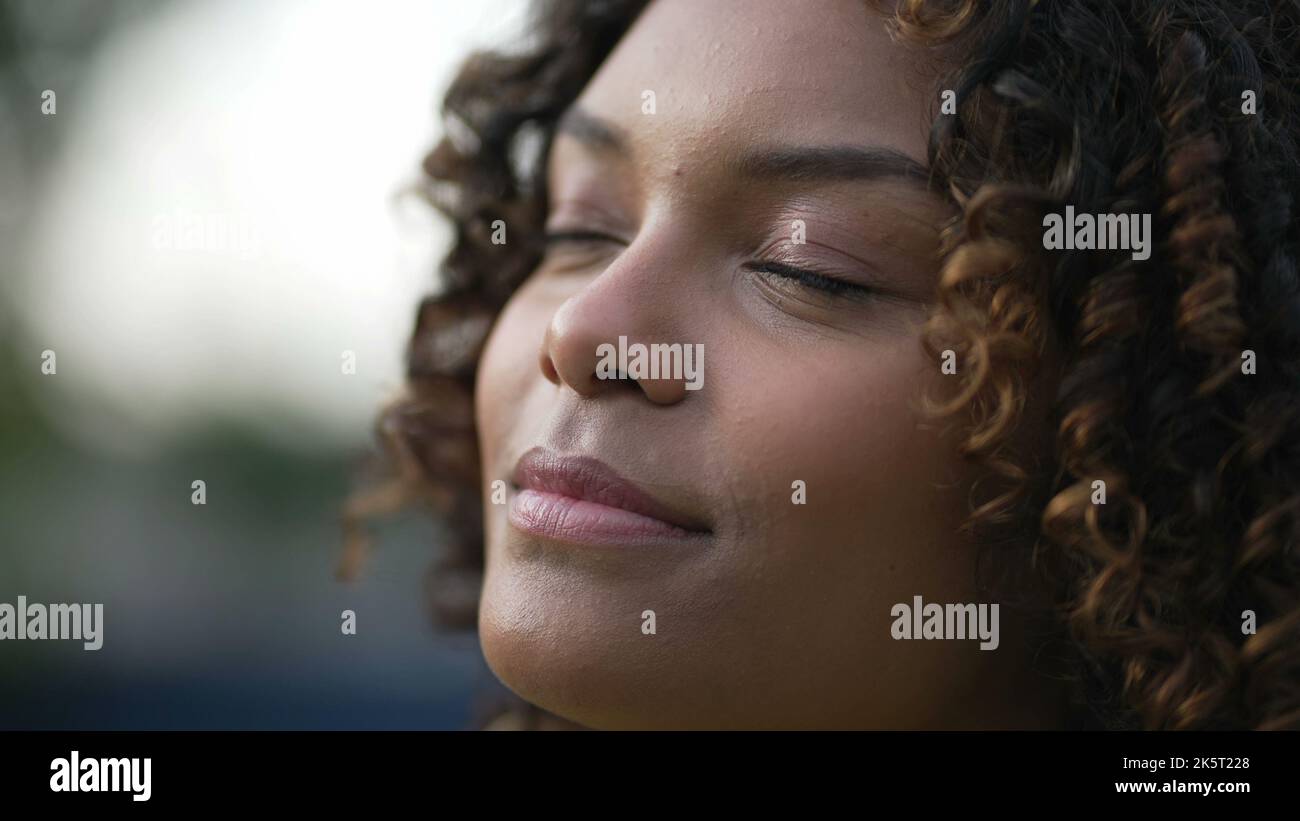 Meditative African American young woman closing eyes in contemplation ...