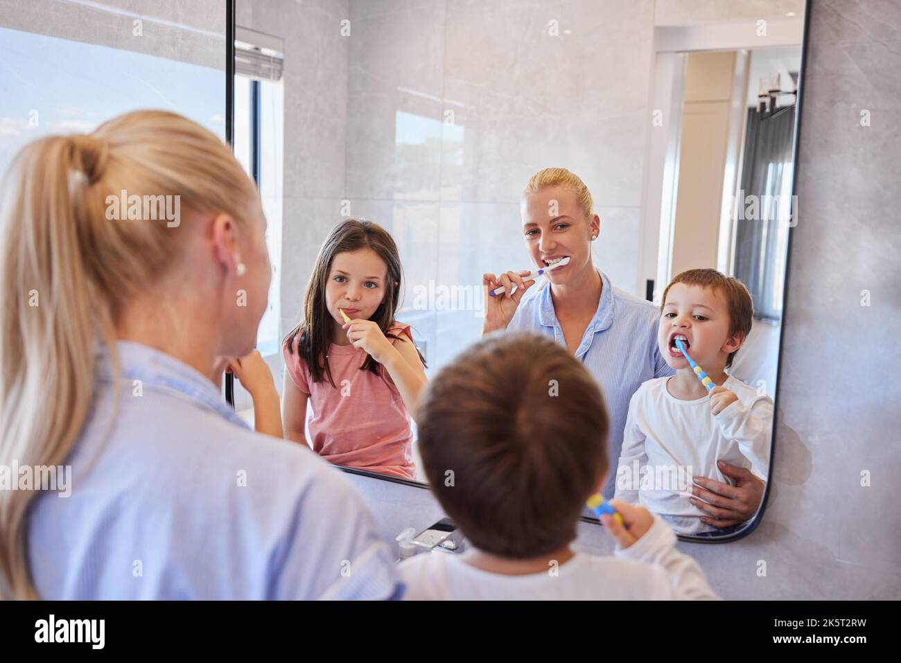 Happy caucasian family using toothbrushes and looking in mirror. Young ...
