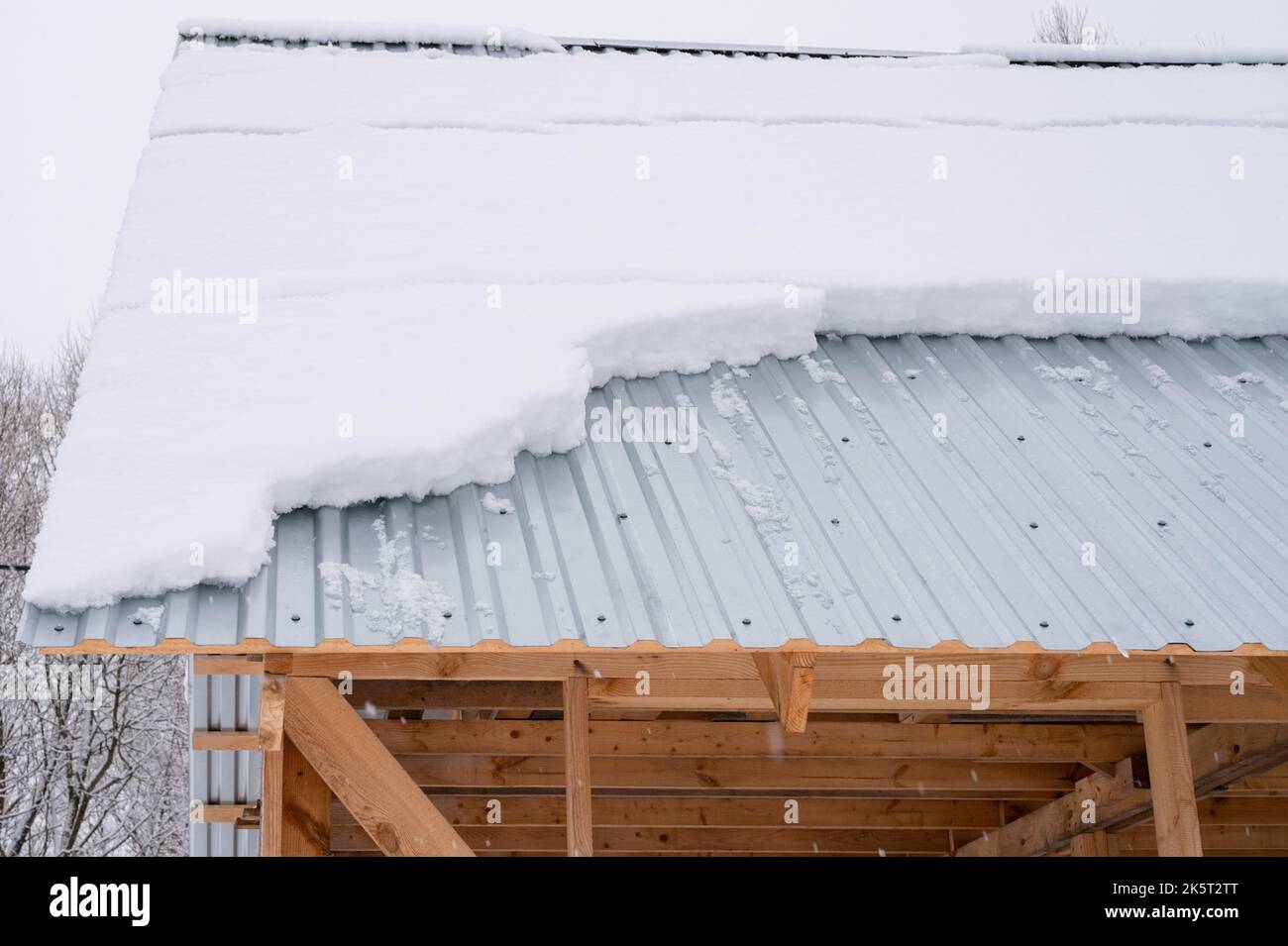 snow sliding down from roof. building construction house with metal ...
