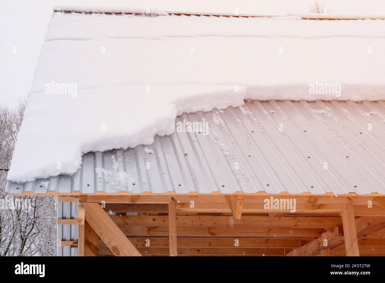 snow sliding down from roof. building construction house with metal ...