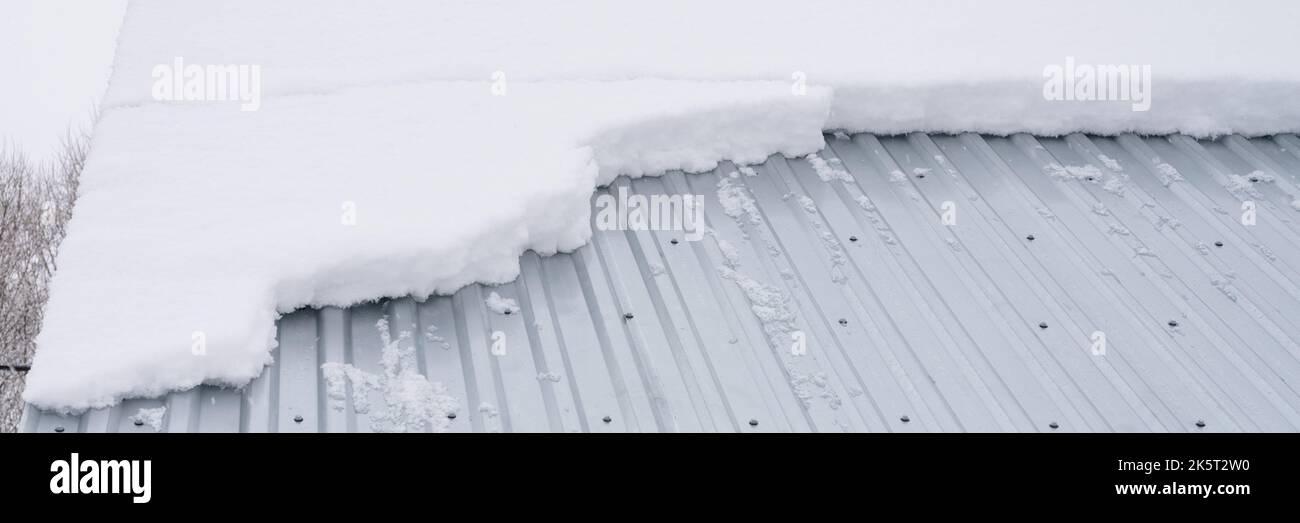 snow sliding down from roof. building construction house with metal ...