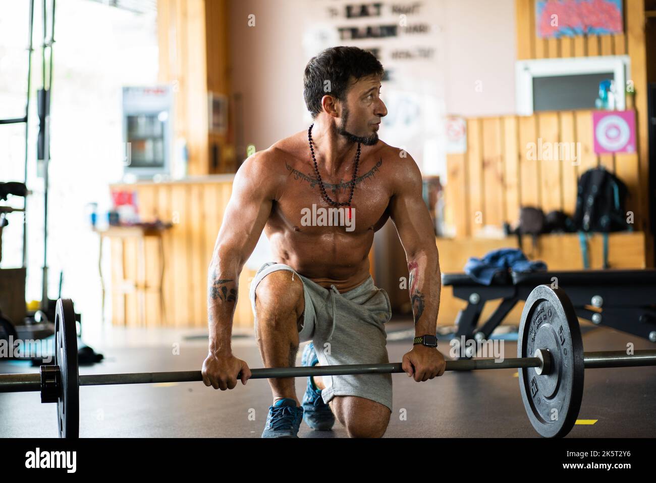 Distracted man resting in a gym while holding a bar with weights Stock ...