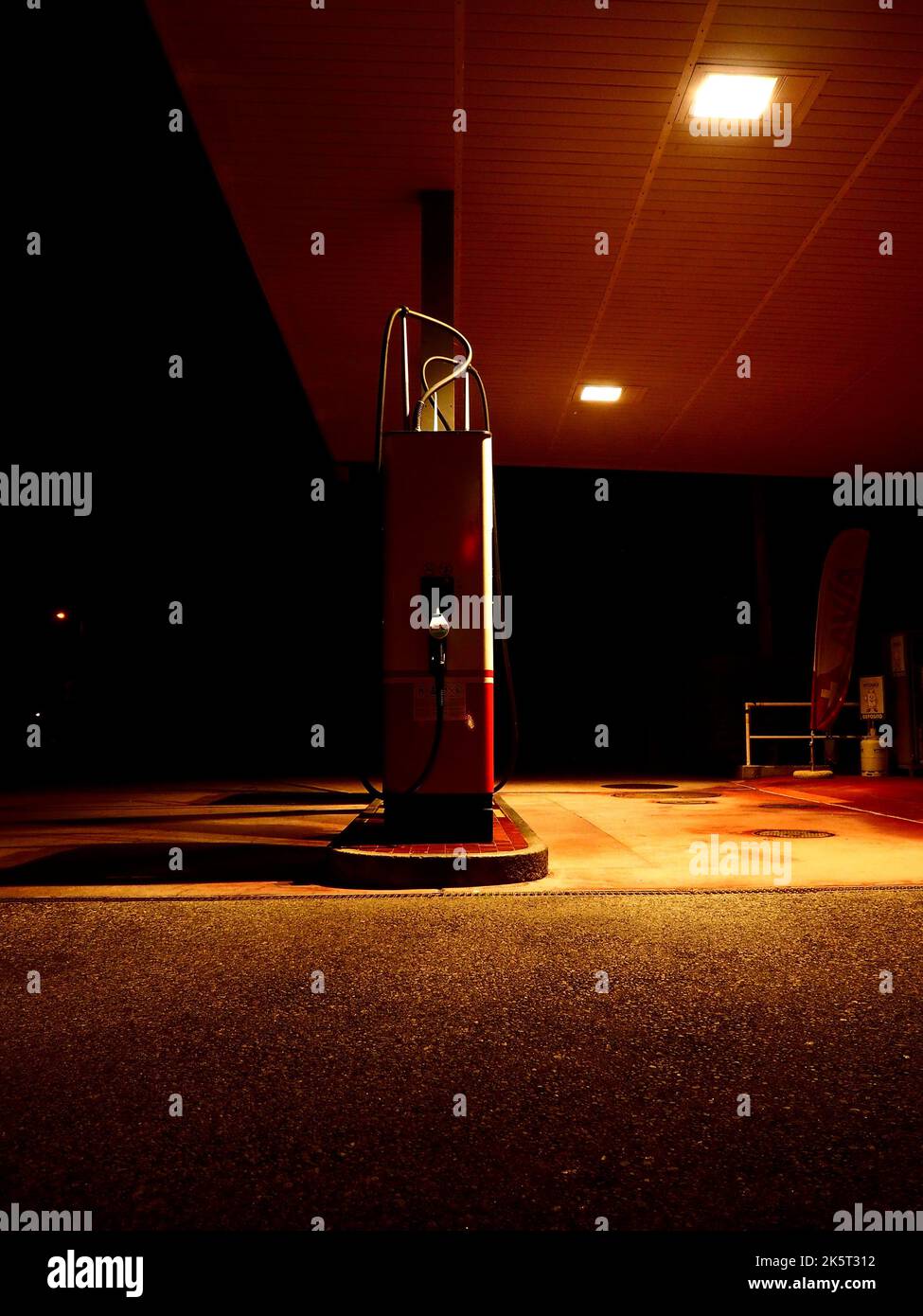 A vertical shot of a fuel dispenser at an empty gas station at night ...