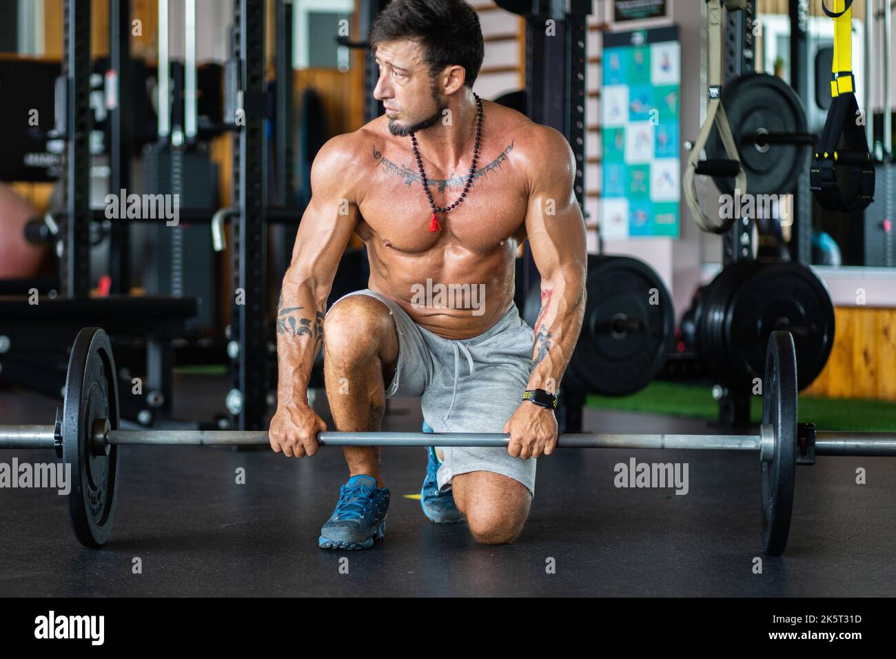 Strong man resting in a gym while exercising with weights Stock Photo ...
