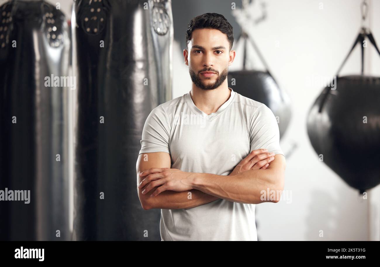 Portrait of one serious young hispanic man standing with his arms ...