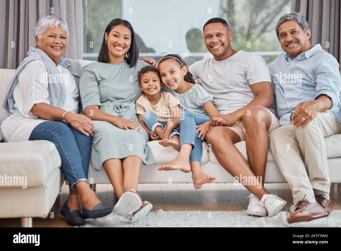 Happy and affectionate young mixed race family of six sitting on a sofa ...