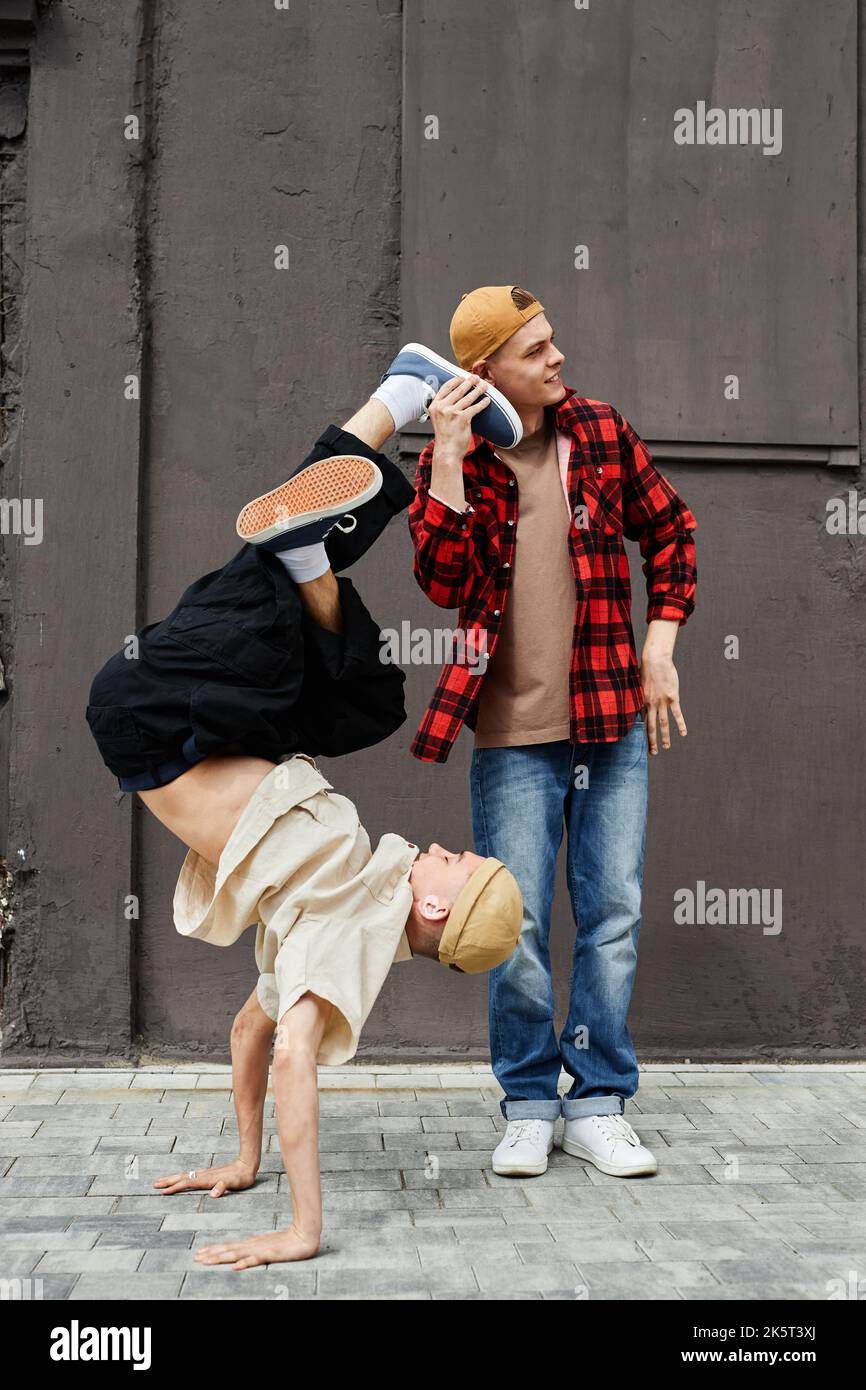 Vertical full length shot of two male dancers doing handstand pose ...