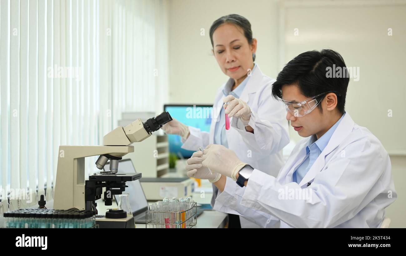 Middle age female scientist and laboratory assistant conducting ...