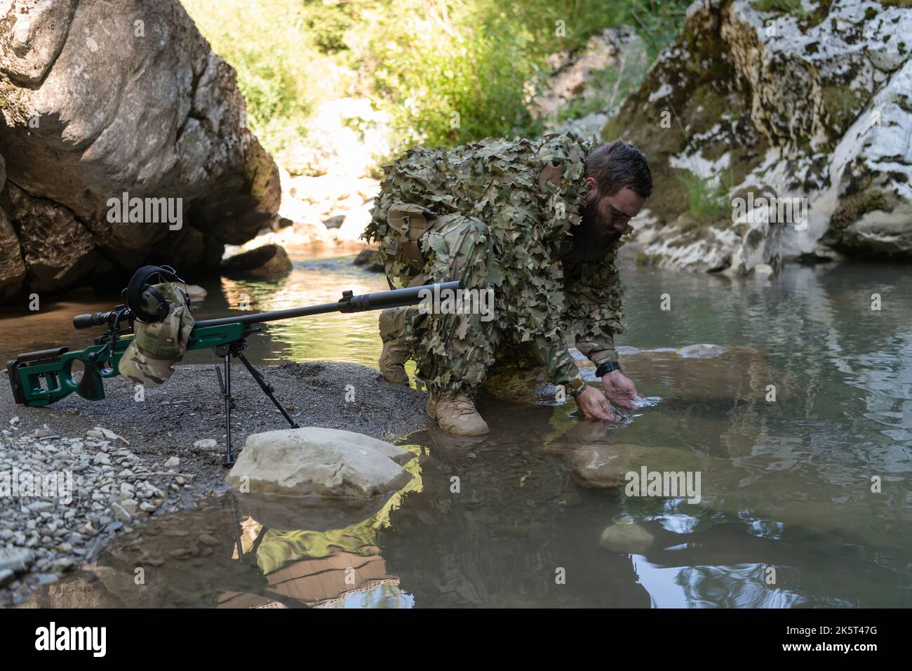 Soldier in a camouflage suit uniform drinking fresh water from the ...