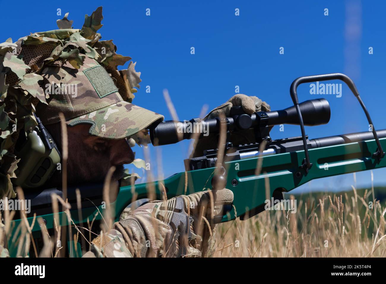 army soldier holding sniper rifle with scope and aiming in forest. war ...
