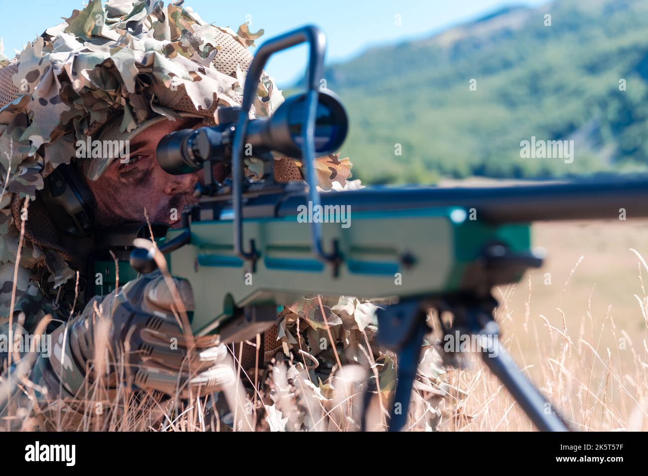 army soldier holding sniper rifle with scope and aiming in forest. war ...