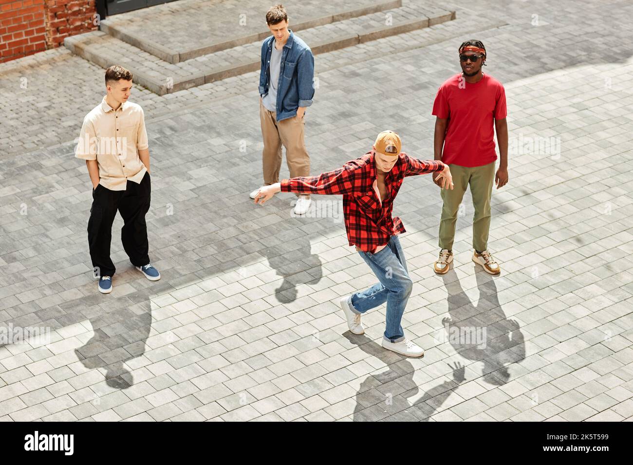 Top view at male breakdancing team performing outdoors in city lit by ...