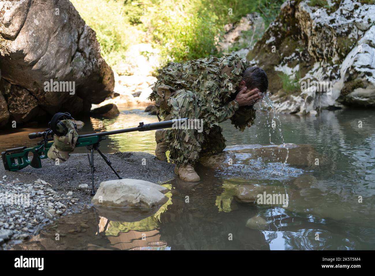 Soldier in a camouflage suit uniform drinking fresh water from the ...