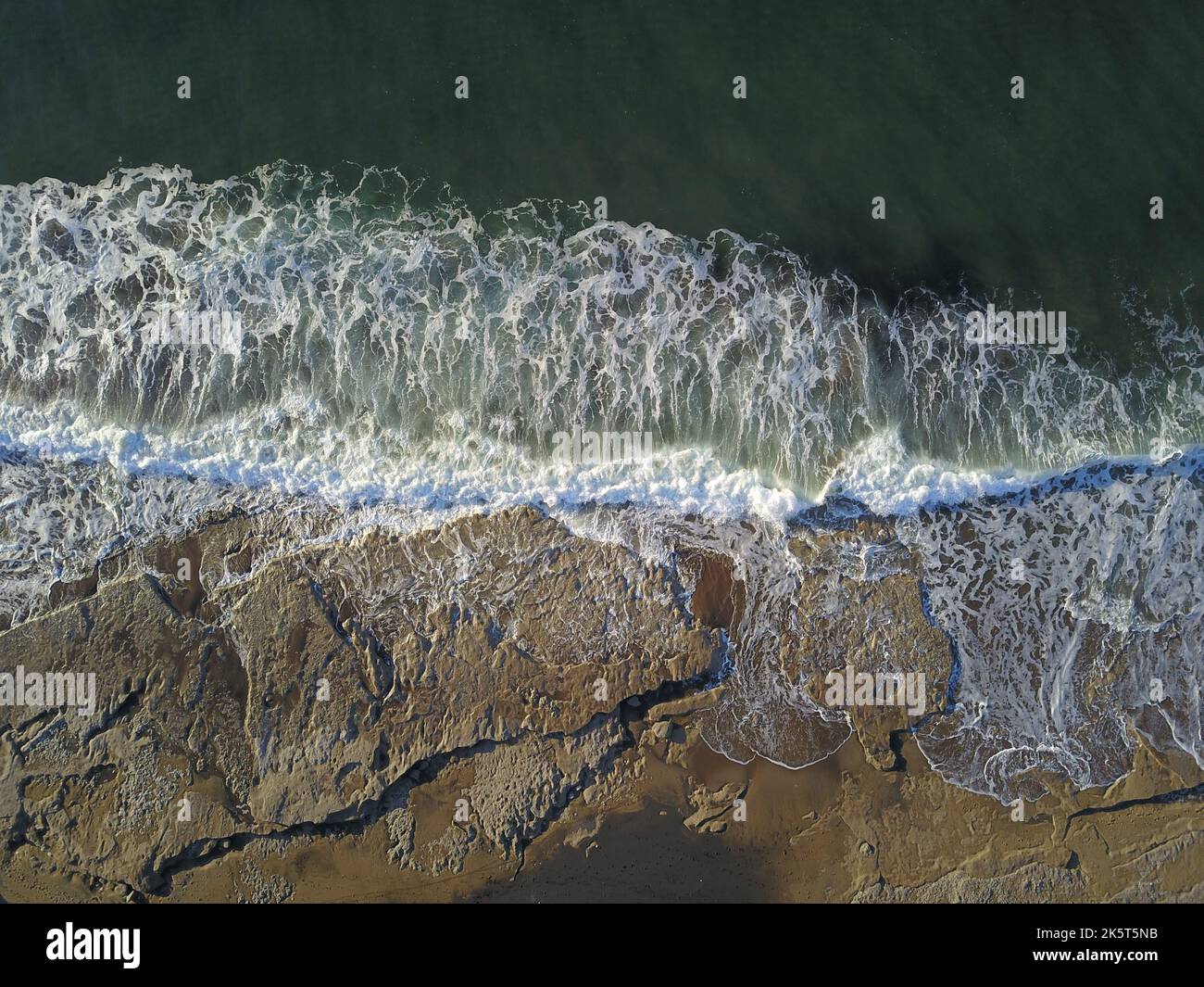 Aerial photograph of a rocky coastline with arriving and breaking ocean ...