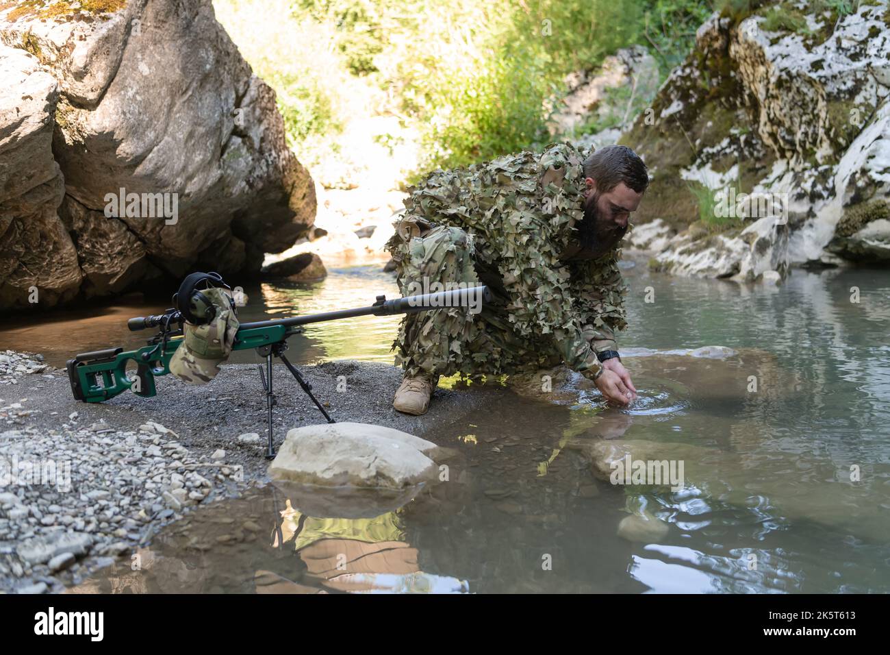 Soldier in a camouflage suit uniform drinking fresh water from the ...