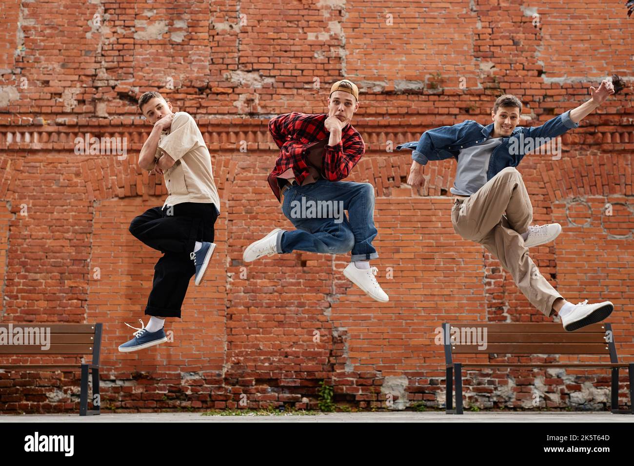 Freeze frame of all male dance team jumping in air and posing against ...