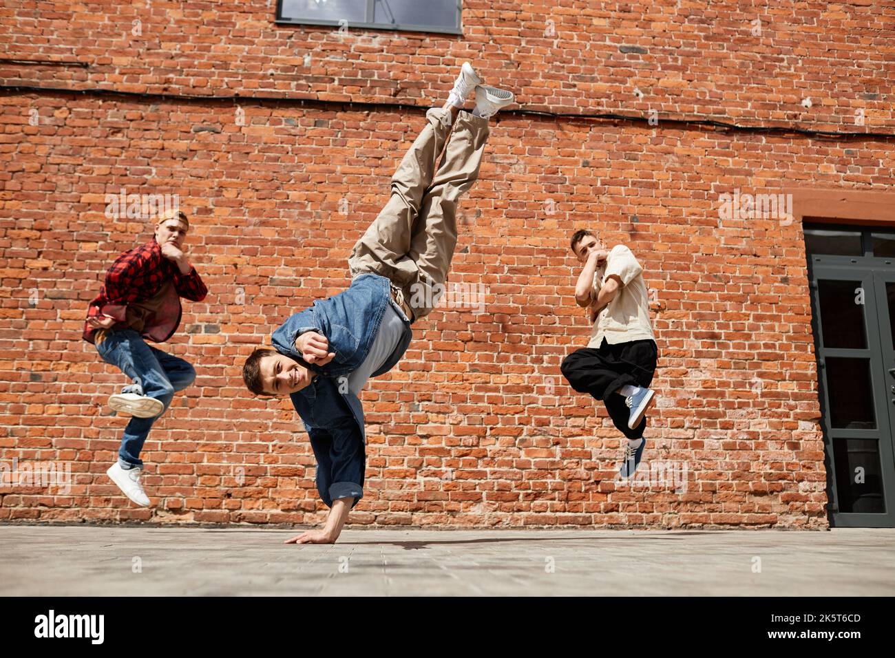 Freeze frame of all male breakdancing team jumping in air and posing ...