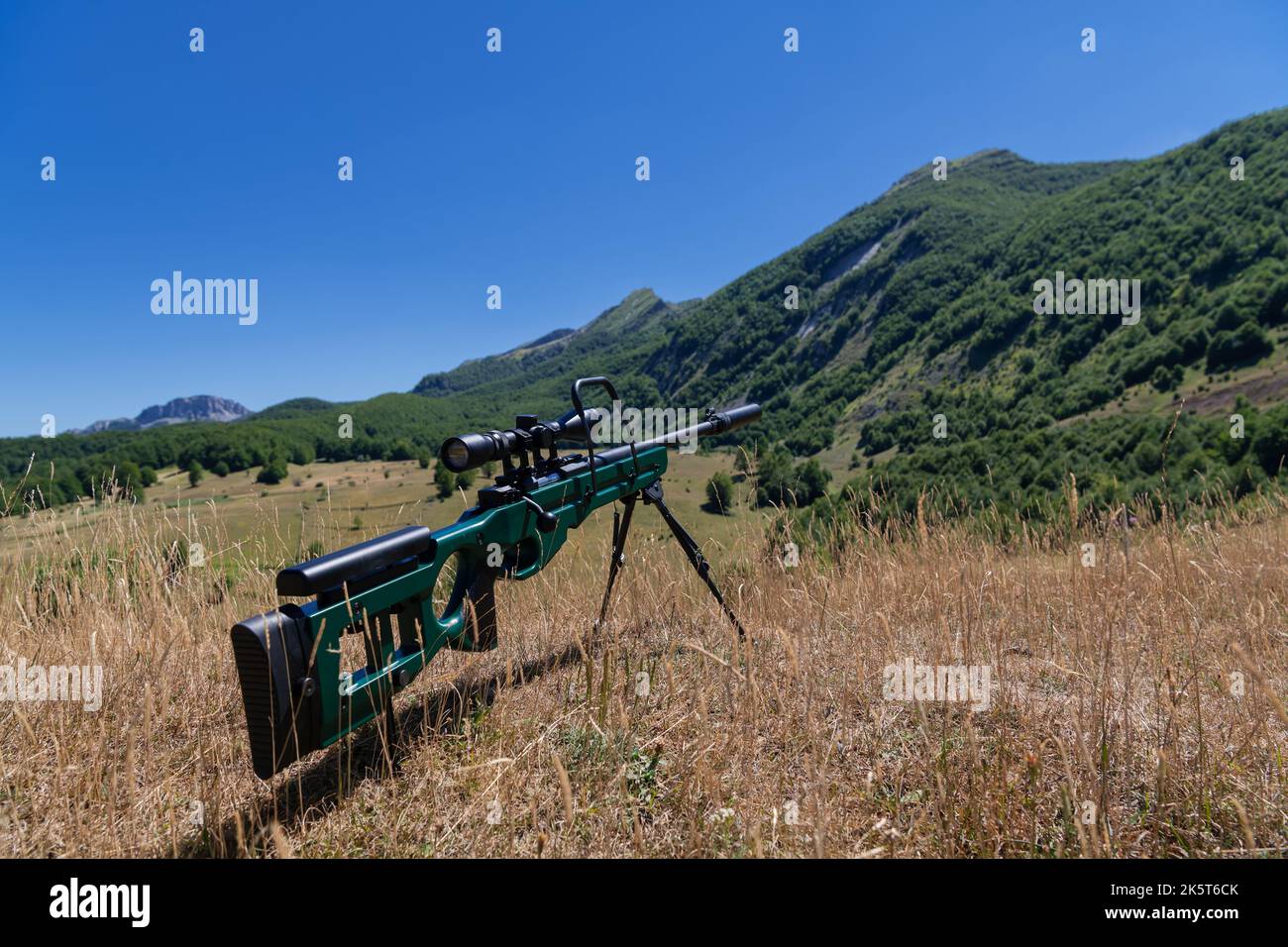 A green military sniper rifle with a scope for long distance tactical ...