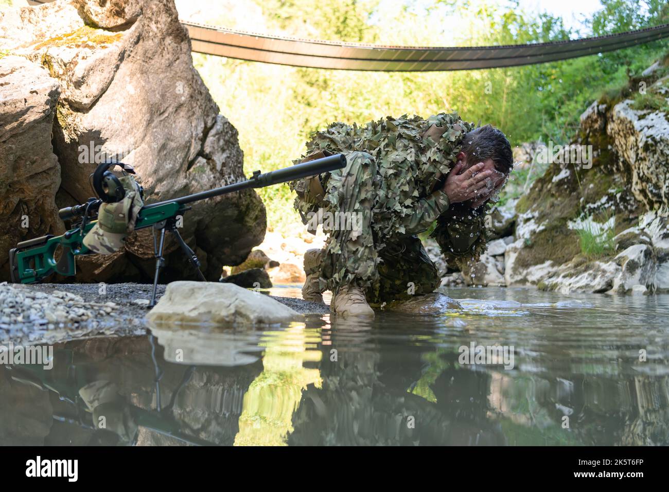 Soldier in a camouflage suit uniform drinking fresh water from the ...