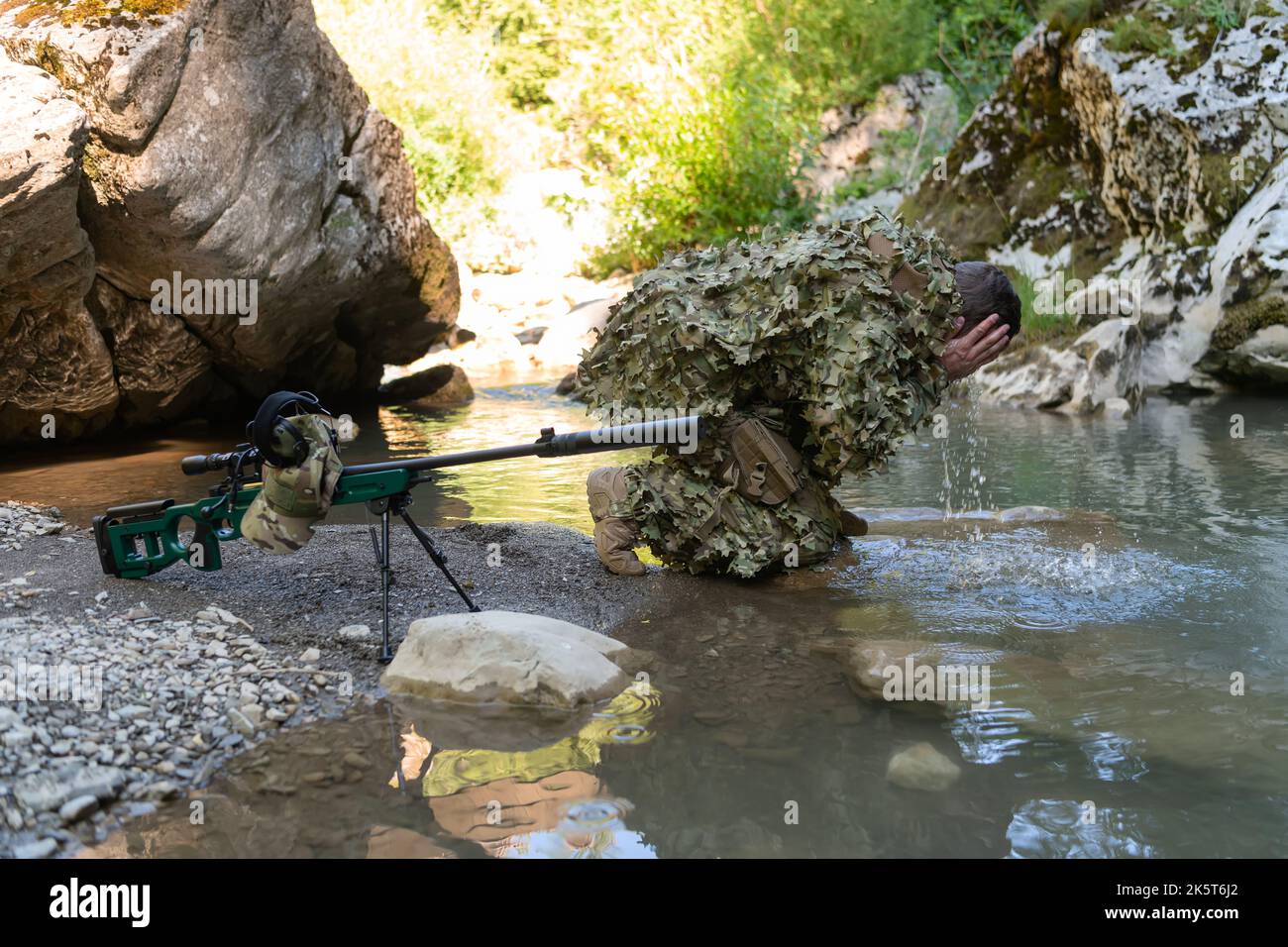 Soldier in a camouflage suit uniform drinking fresh water from the ...