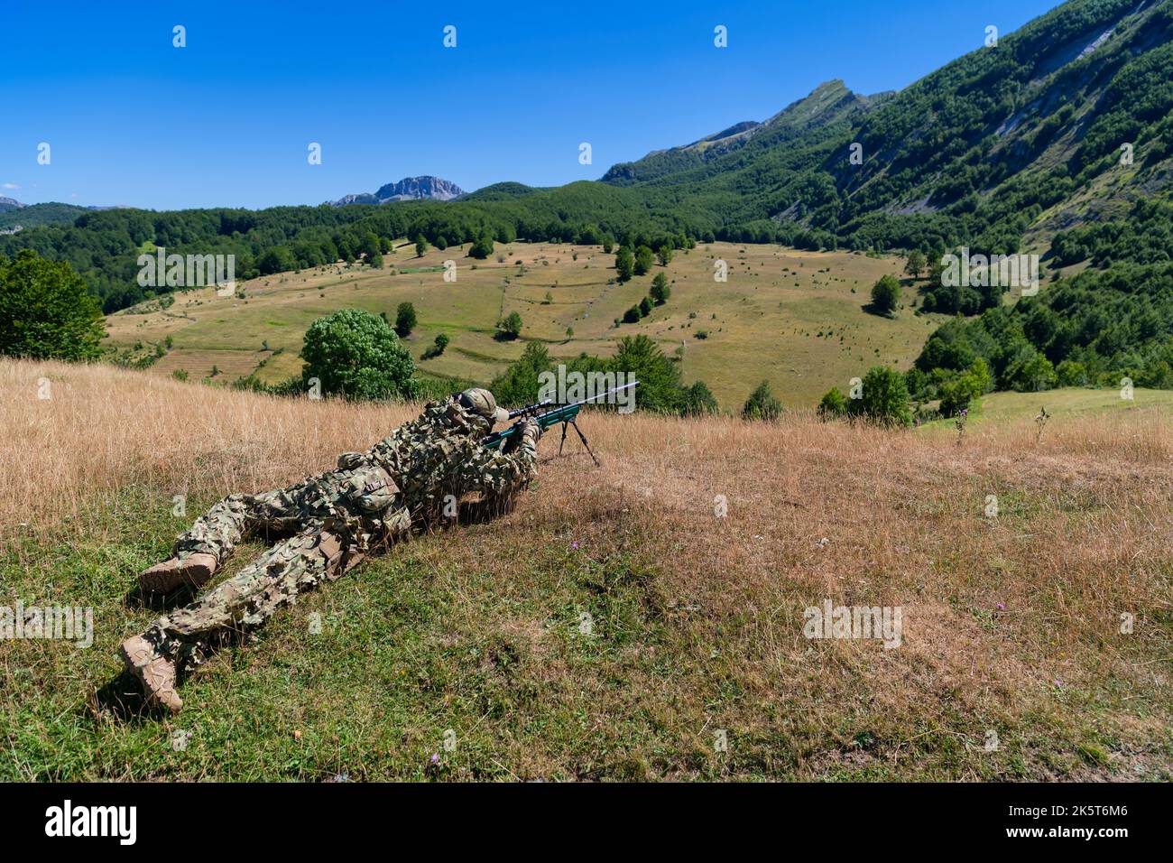 army soldier holding sniper rifle with scope and aiming in forest. war ...