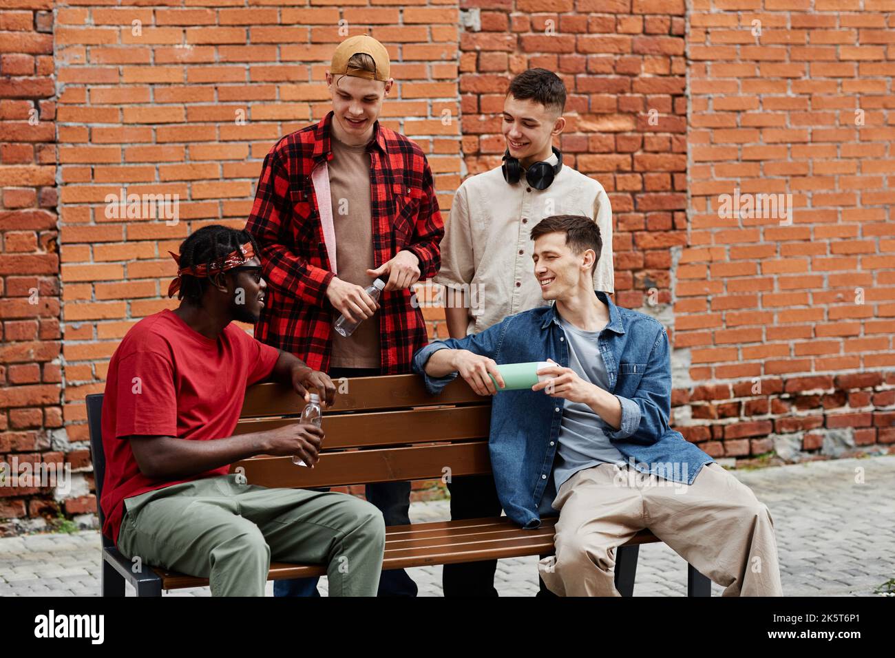 Diverse group of young guys wearing streetstyle fashion while sitting ...