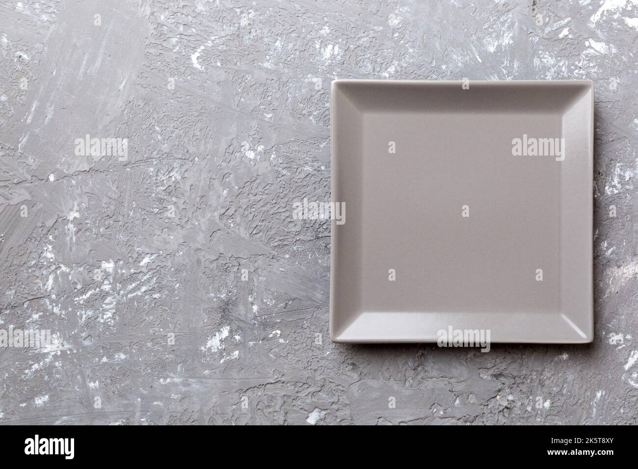 Top view of empty square plate on cement background. Empty space for ...