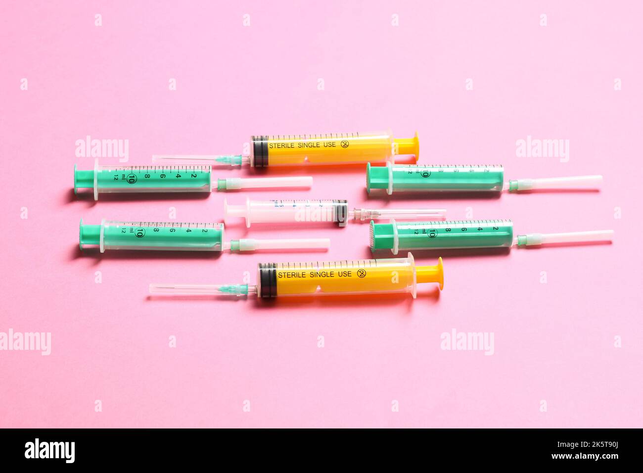 Top view of medical syringes with needles at pink background with copy ...