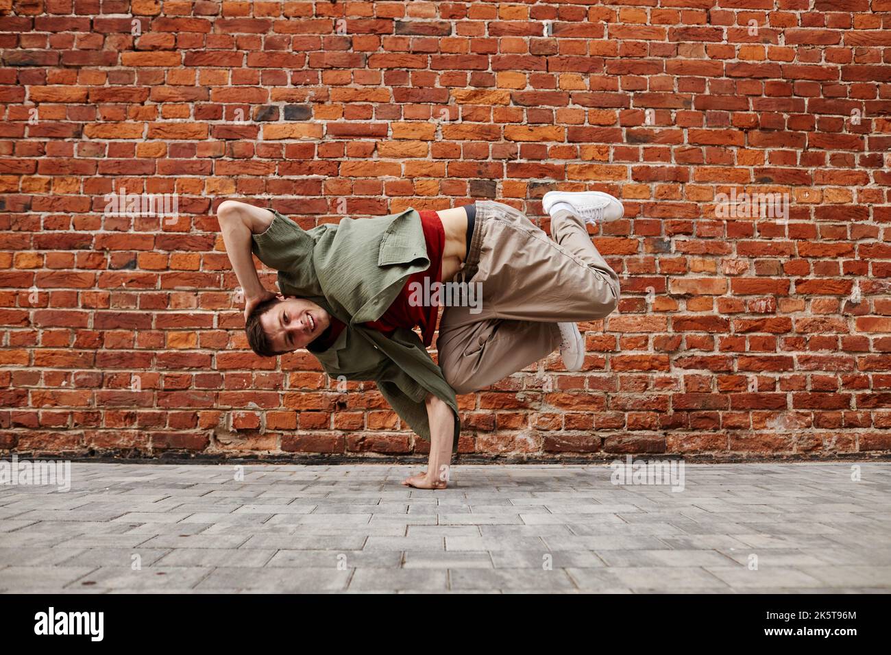 Full length action shot of male dancer doing handstand pose outdoors ...