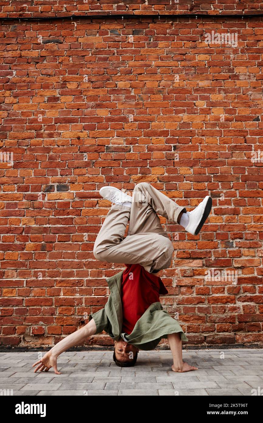 Vertical shot of young man doing breakdance headstand pose against ...