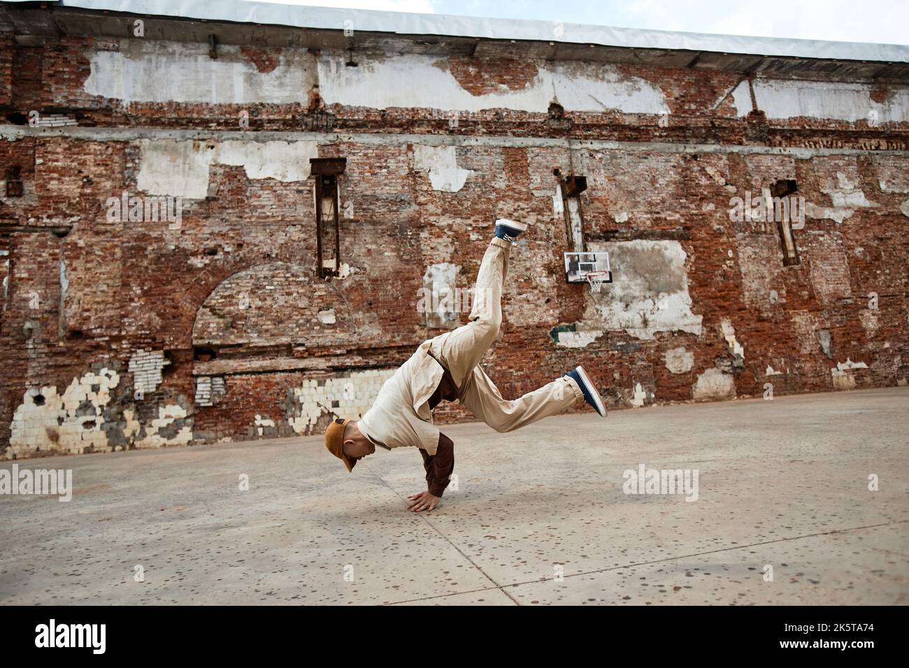 Wide angle shot of young man doing breakdance handstands outdoors in ...