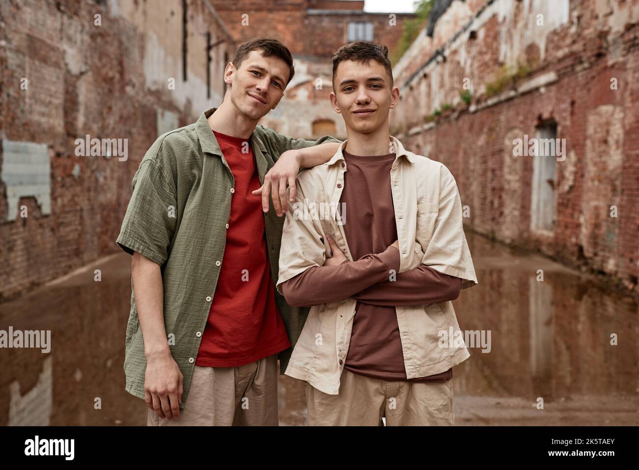 Neutral waist up portrait of two twin guys looking at camera in shabby ...