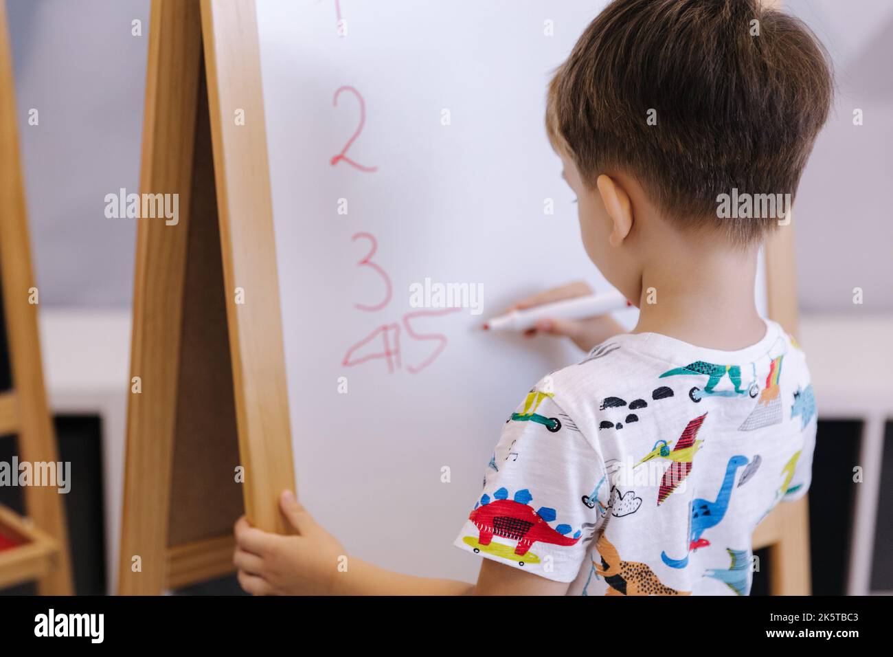 Little boy writes numbers on a board. Kindergarten Stock Photo - Alamy