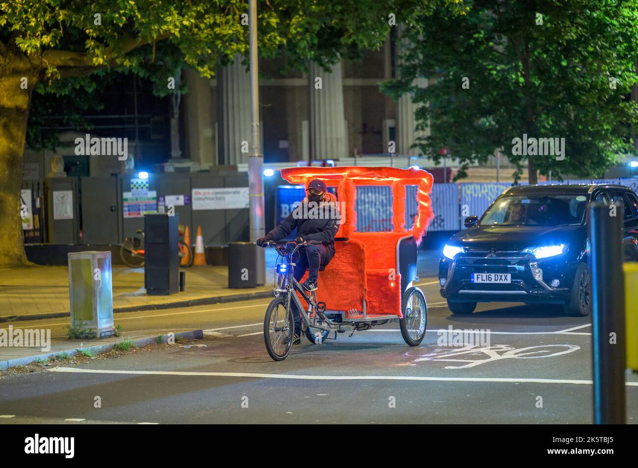LONDON - May 21, 2022: Male rickshaw driver wears face mask and cap in ...