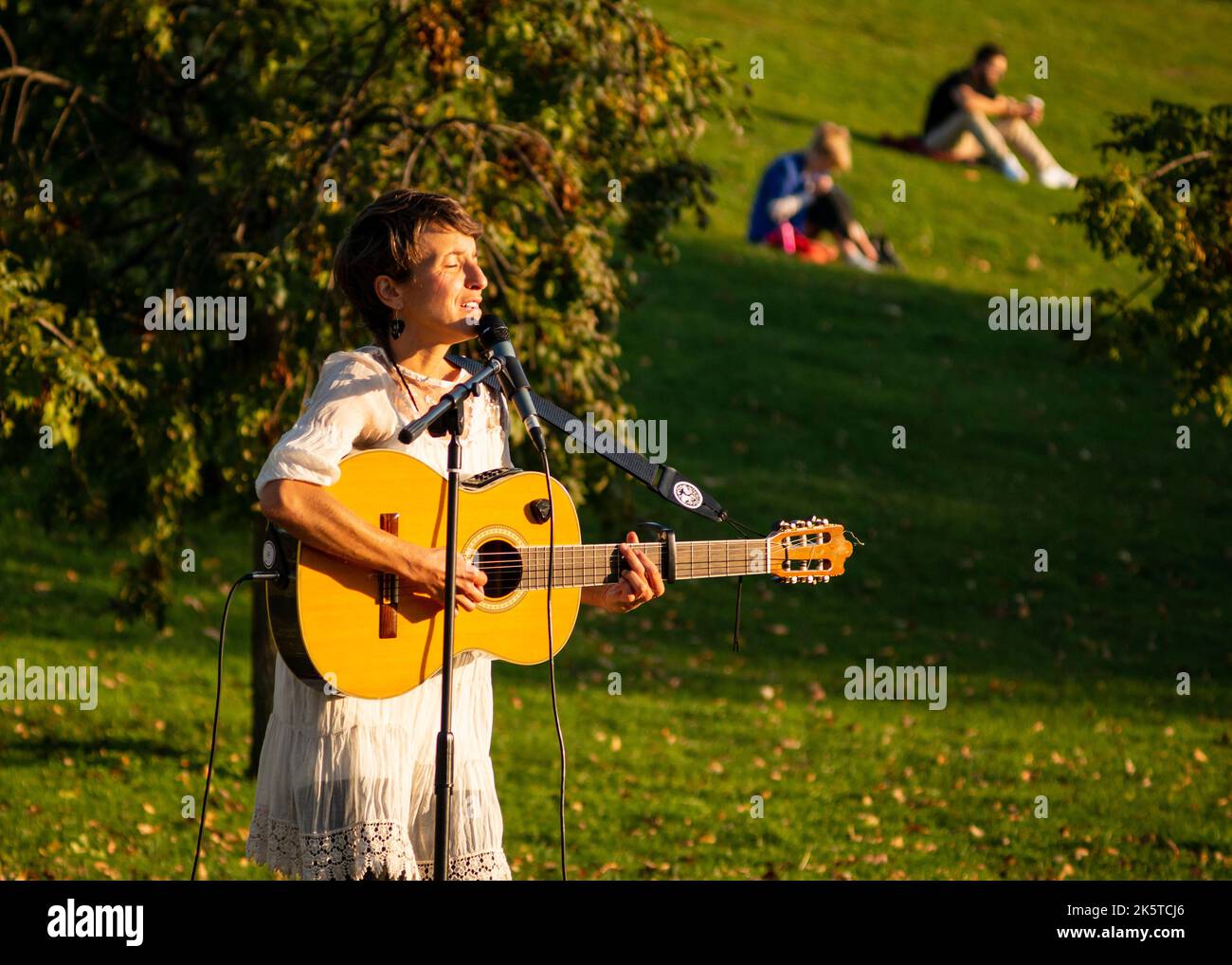 Female street musician with acoustic guitar performing in park in Sofia ...