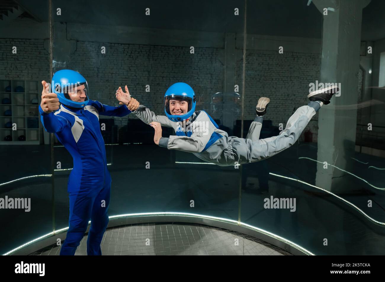 A man teaches a woman how to fly in a wind tunnel. Free fall simulator ...