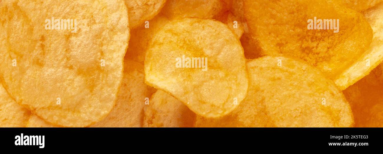 Potato chips texture, a salty snack panorama, a pile of yellow crisps ...