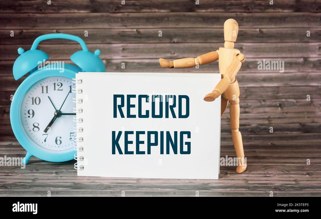 Keeping records text on notepad and wooden background with clock ...