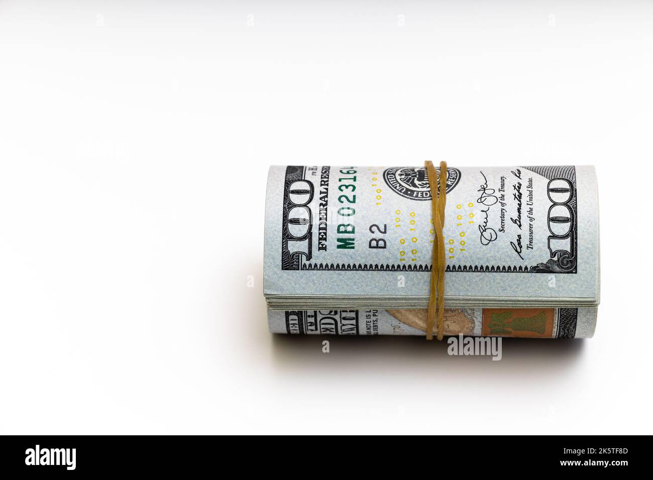 one hundred dollar bill rolled into a tube. stack of us dollars ...