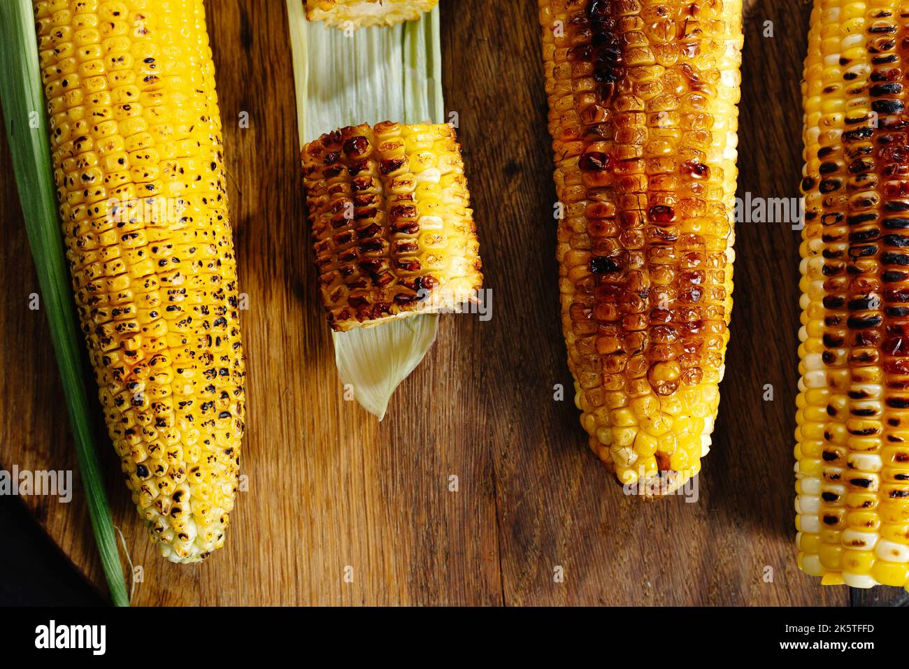 Roasted barbecue corn. Grilled corn on a dark wooden background. Slices ...