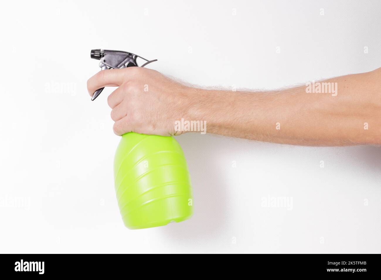 male hand holding a green spray gun on a white background Stock Photo ...